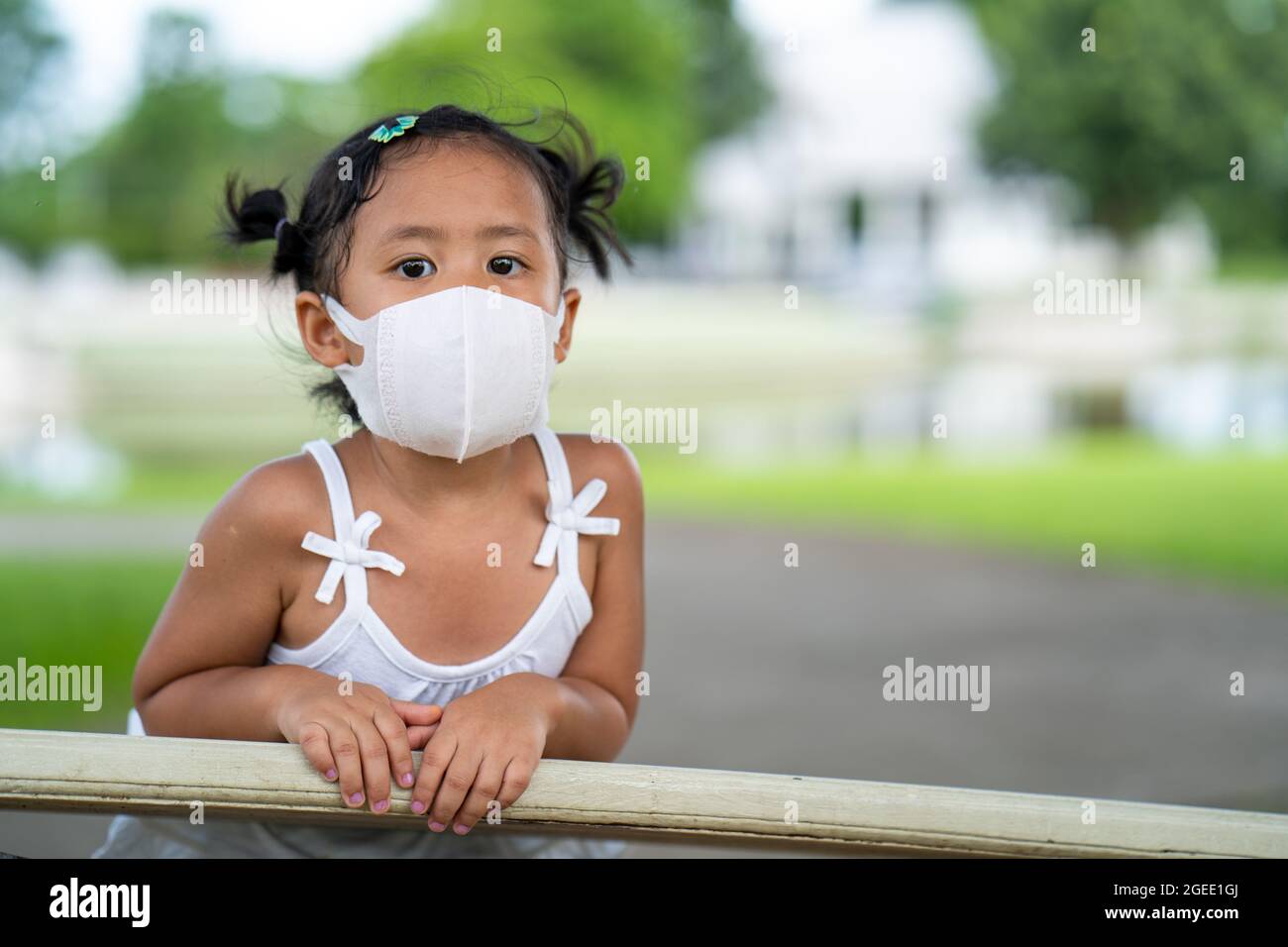 Beautiful Southeast Asian female kid in the park with a mask on her ...