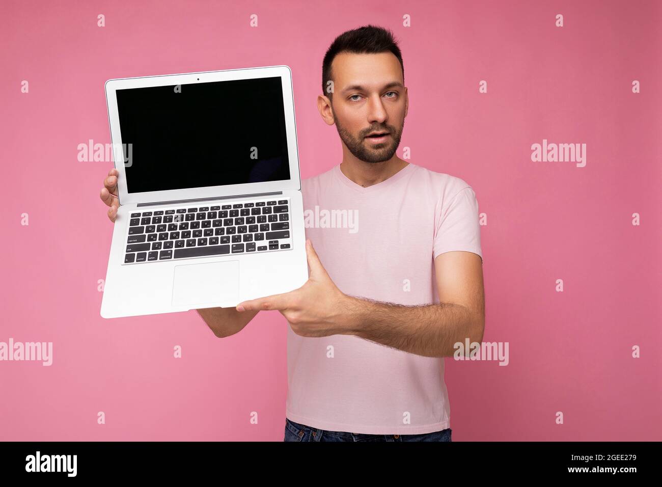 Handsome brunet man holding laptop computer looking at camera in t ...