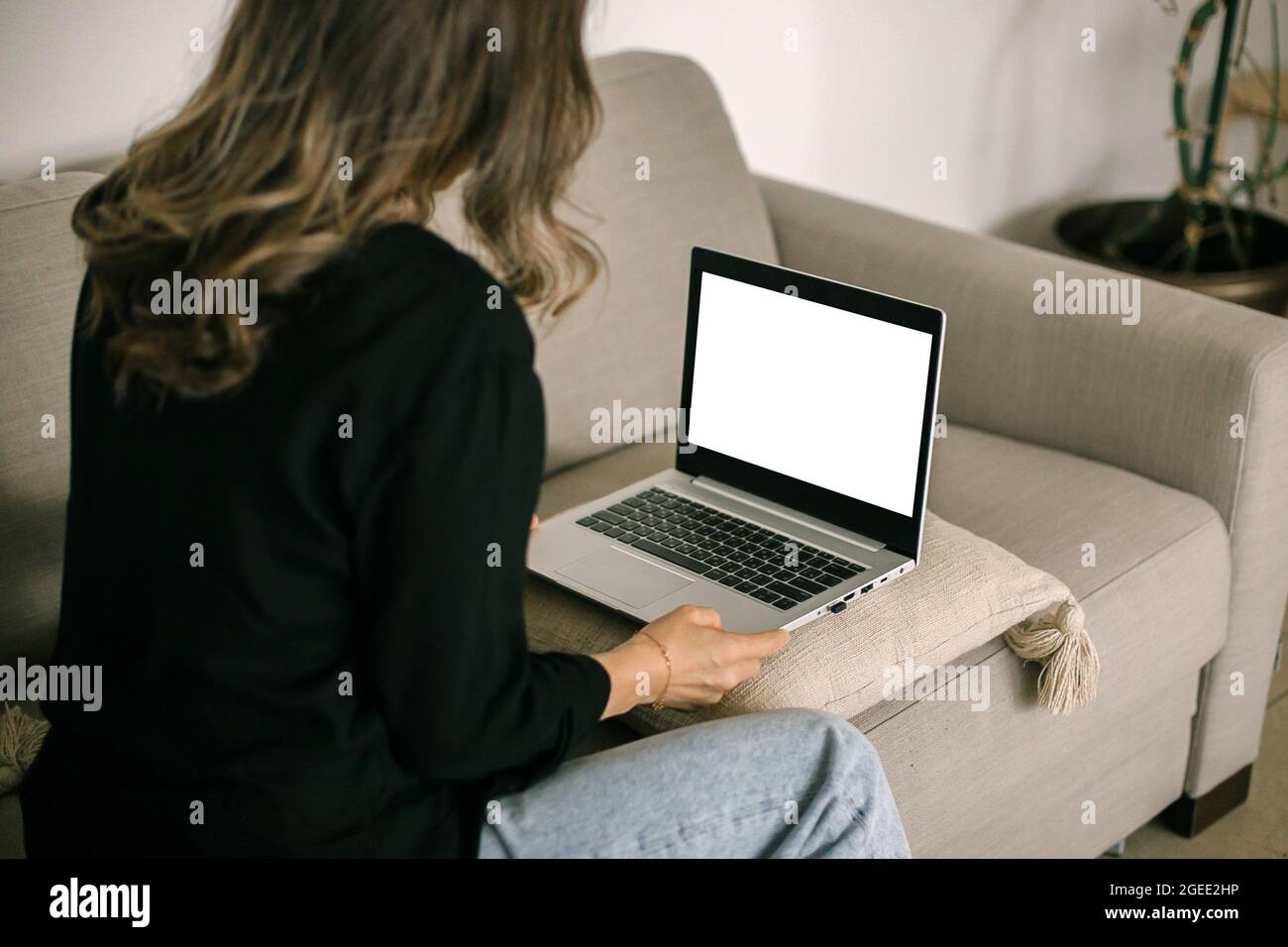 White screen on laptop. Mock up. Young woman working remotely on laptop ...