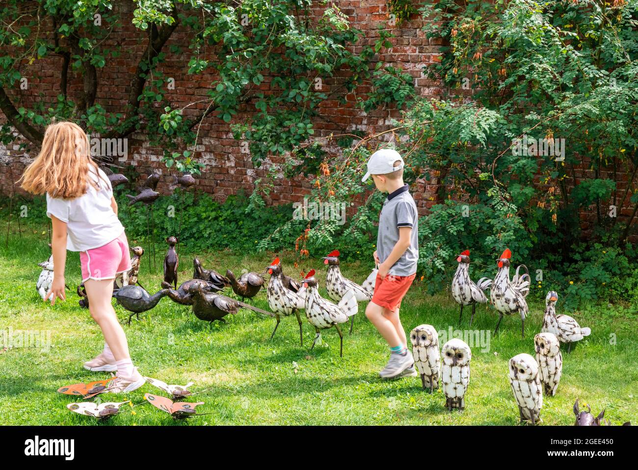 Small bird and animal sculptures displayed in park admired by a couple ...