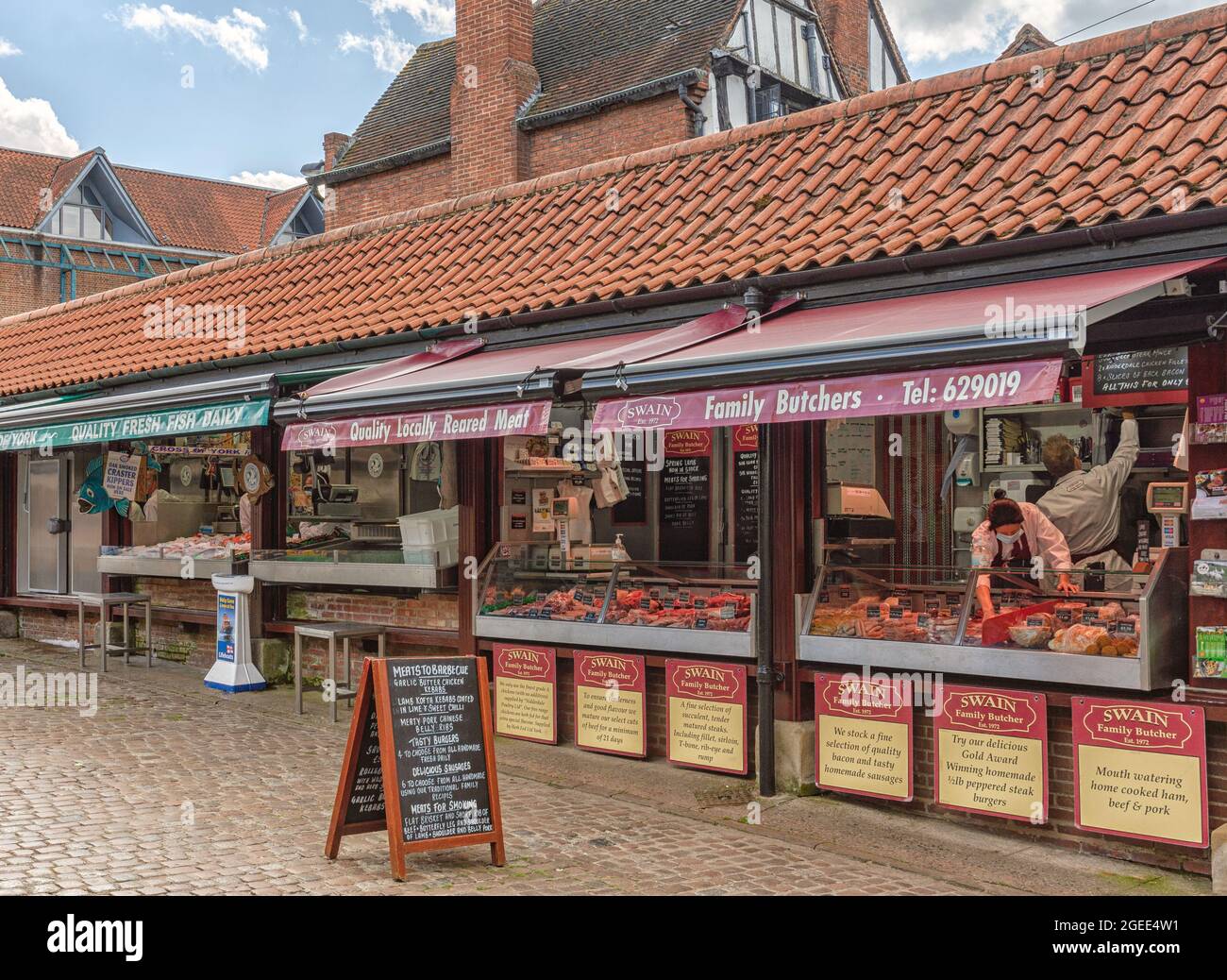 Permanent market stalls selling meat and fish. Produce is displayed in ...