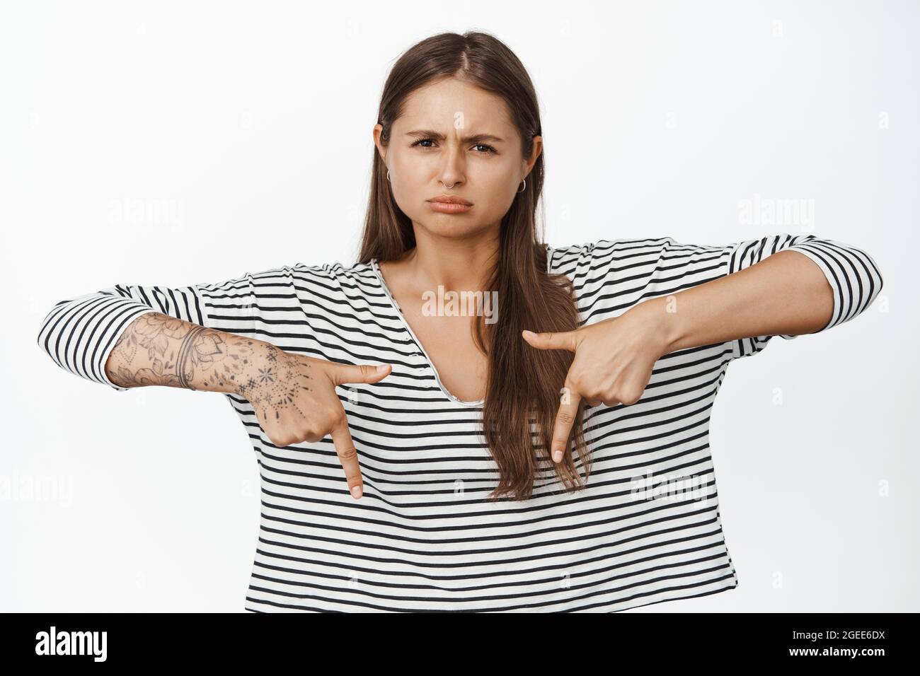Skeptical girl pointing fingers down, squinting eyes, being suspicious ...