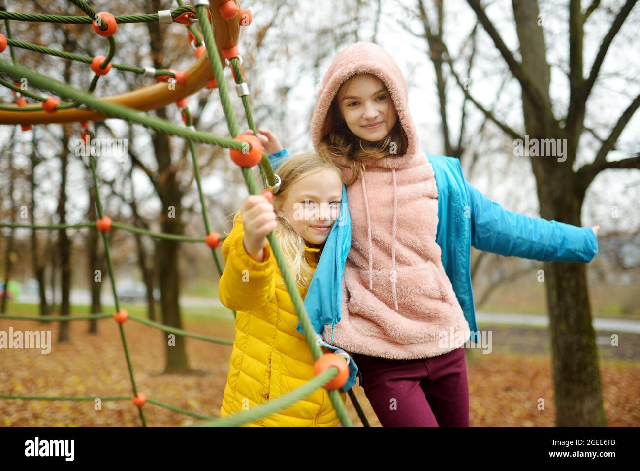 Two adorable young girls having fun on a playground together in ...