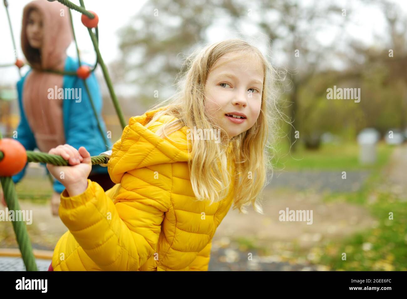 Two adorable young girls having fun on a playground together in ...
