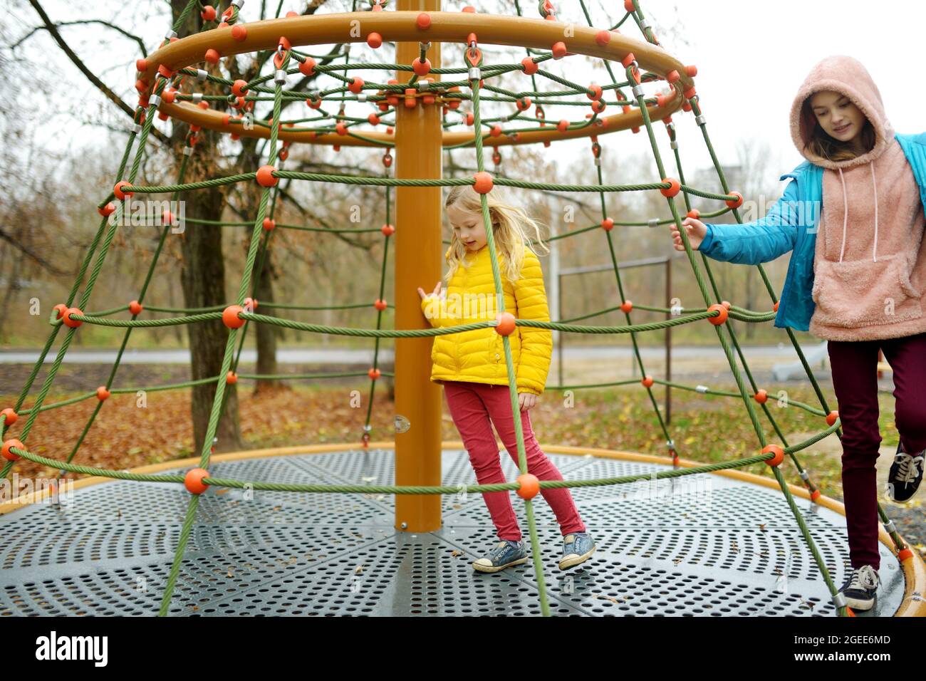 Two adorable young girls having fun on a playground together in ...