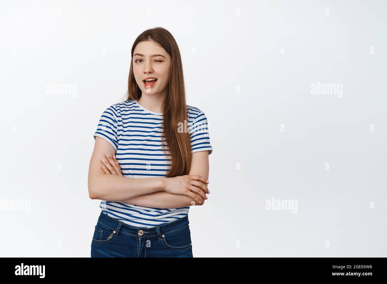 Confident young woman winking, standing like a professional with arms ...