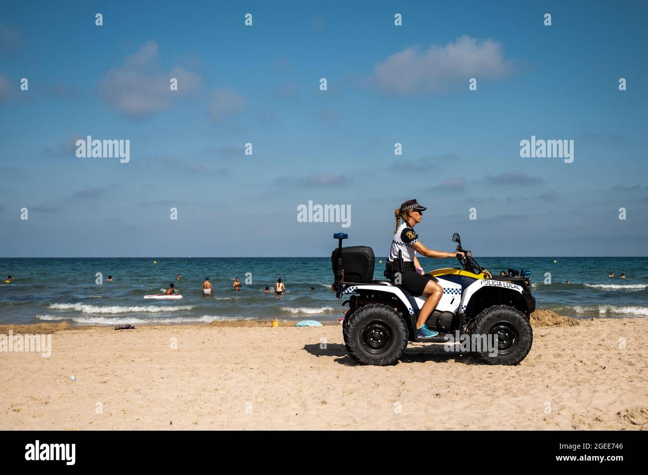 A local police officer patrols in a quad as tourist are bathing ...