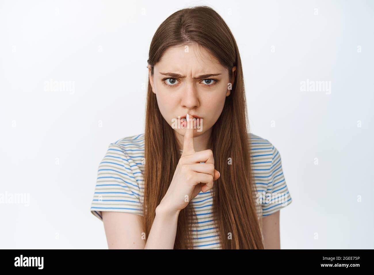 Close up portrait of angry girl shushing, hush gesture, frowning and ...