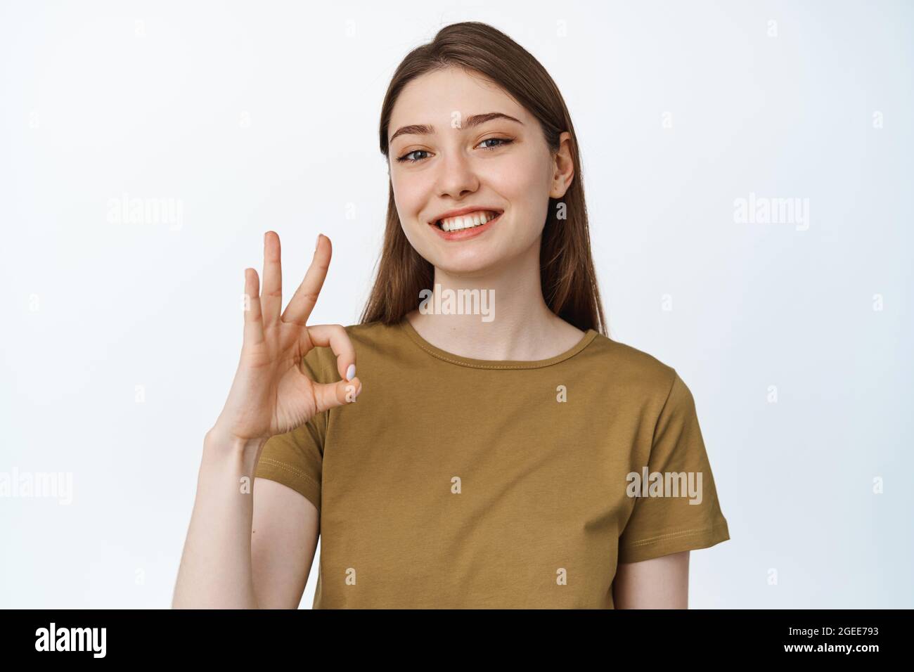 Smiling young woman showing okay, ok sign and looking satisfied ...