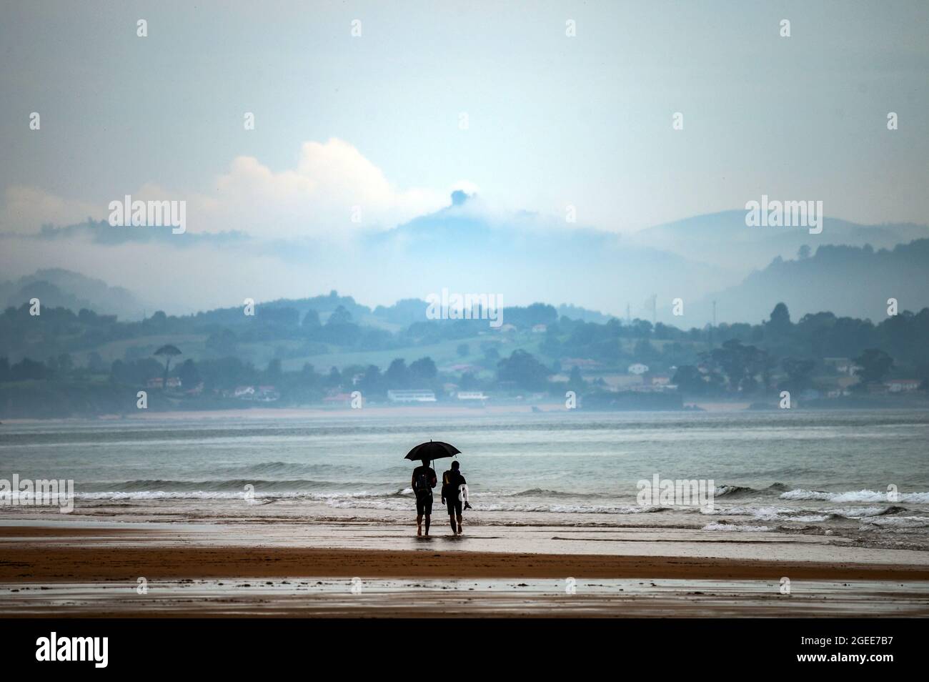 Two men walking under the rain with an umbrella in Vega Beach, near ...