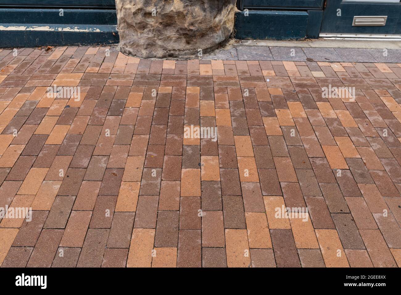 Orange brick sidewalk beside a building with rusticated stone pillar ...