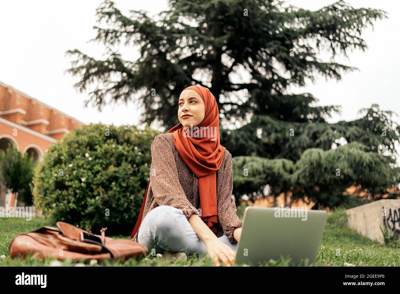 Stock Photo of Muslim woman using computer siting on the grass. she is ...
