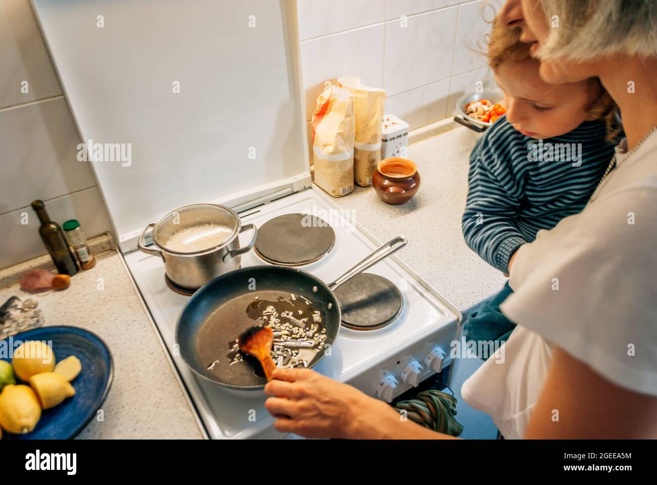 A woman cooks dinner at home with a child in her arms Stock Photo - Alamy