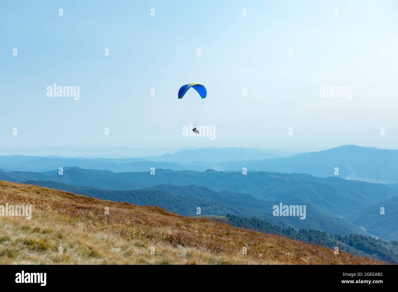 Paragliding over mountains with parachute. Paragliding behind blue sky ...