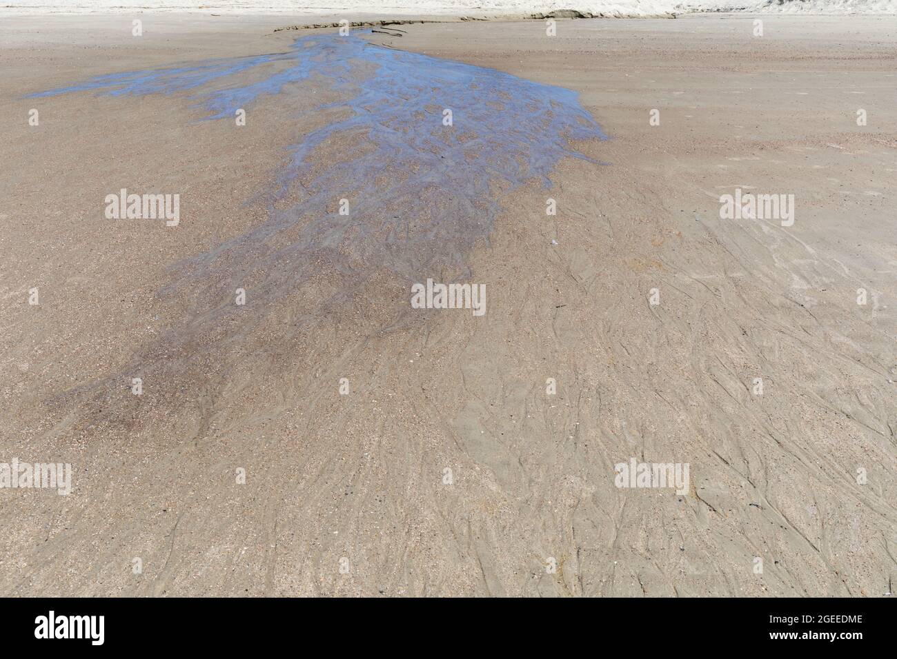 Water discharge creeping across beach sand, creative copy space ...