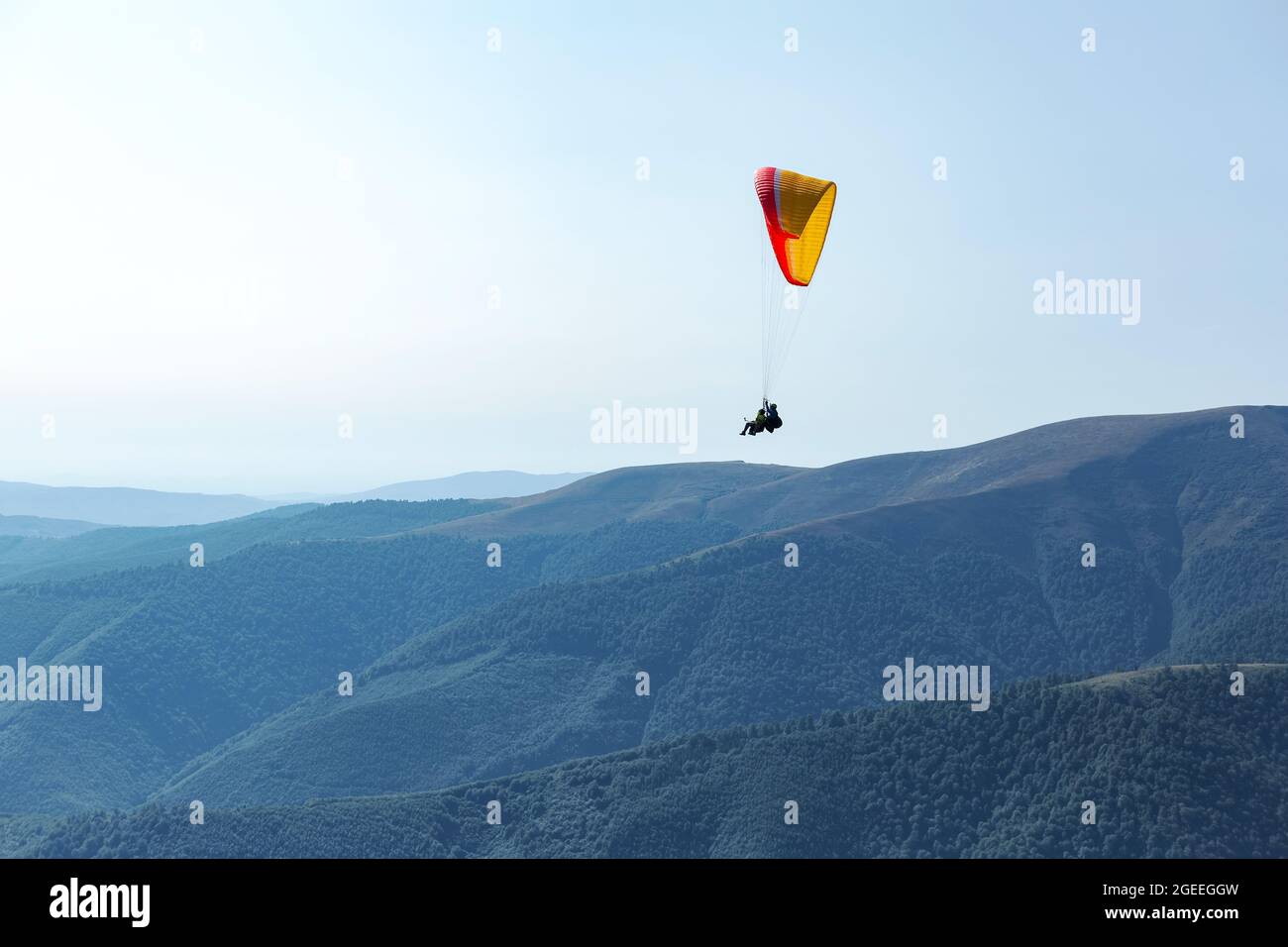 Man on paraglider is flying in the air using a parachute over the ...