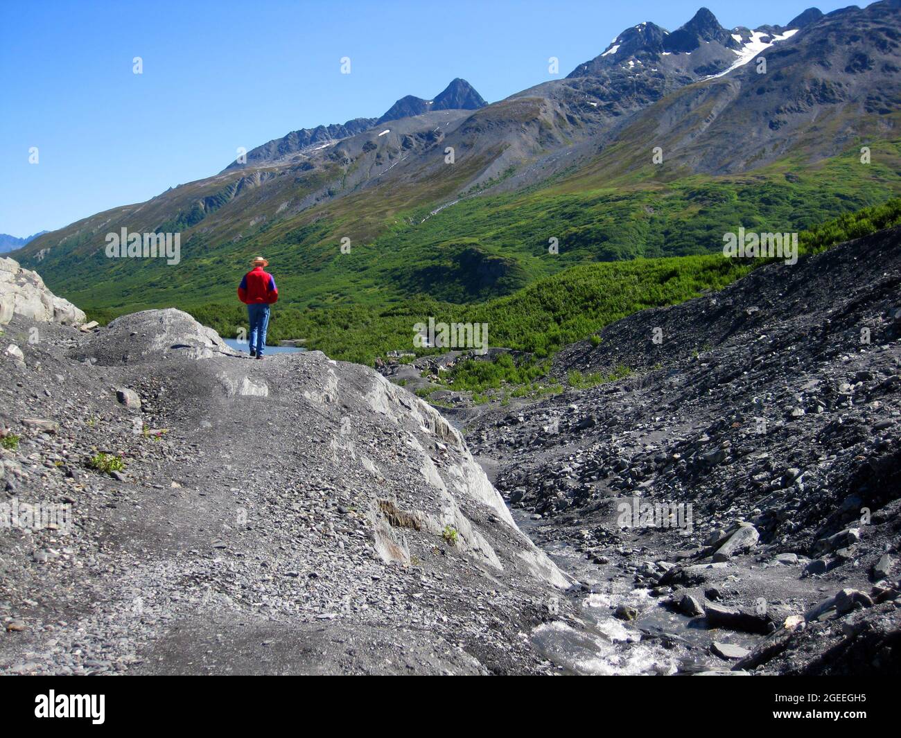 Man hikes around the Worthington Glacier in Alaska. Glacier lake sits ...