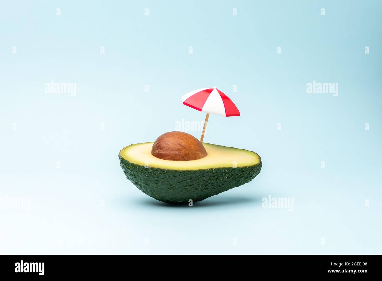 Tropical beach concept made with avocado fruit and sun umbrella ...