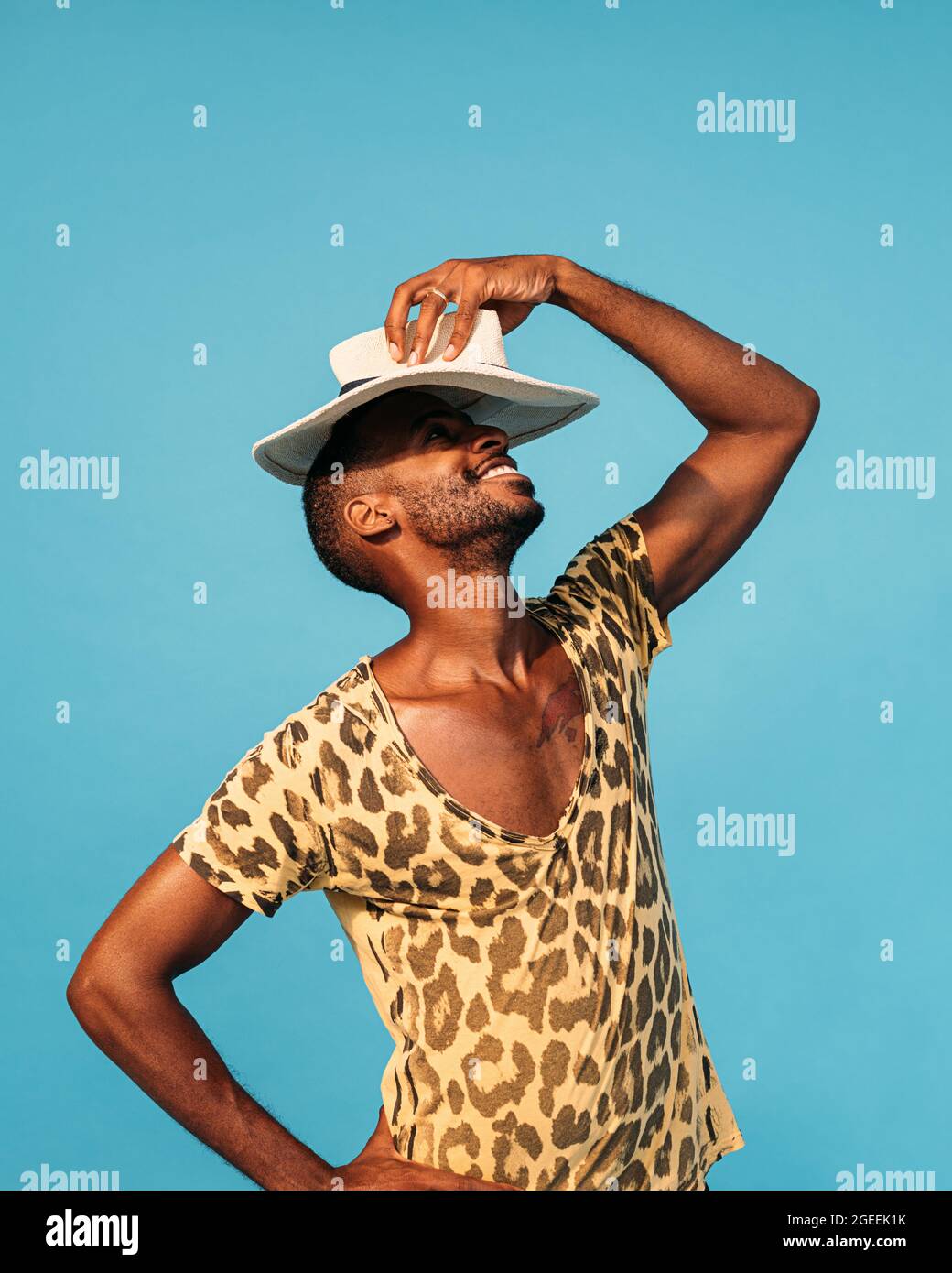 Cheerful guy in stylish clothes holding straw hat under his head in ...