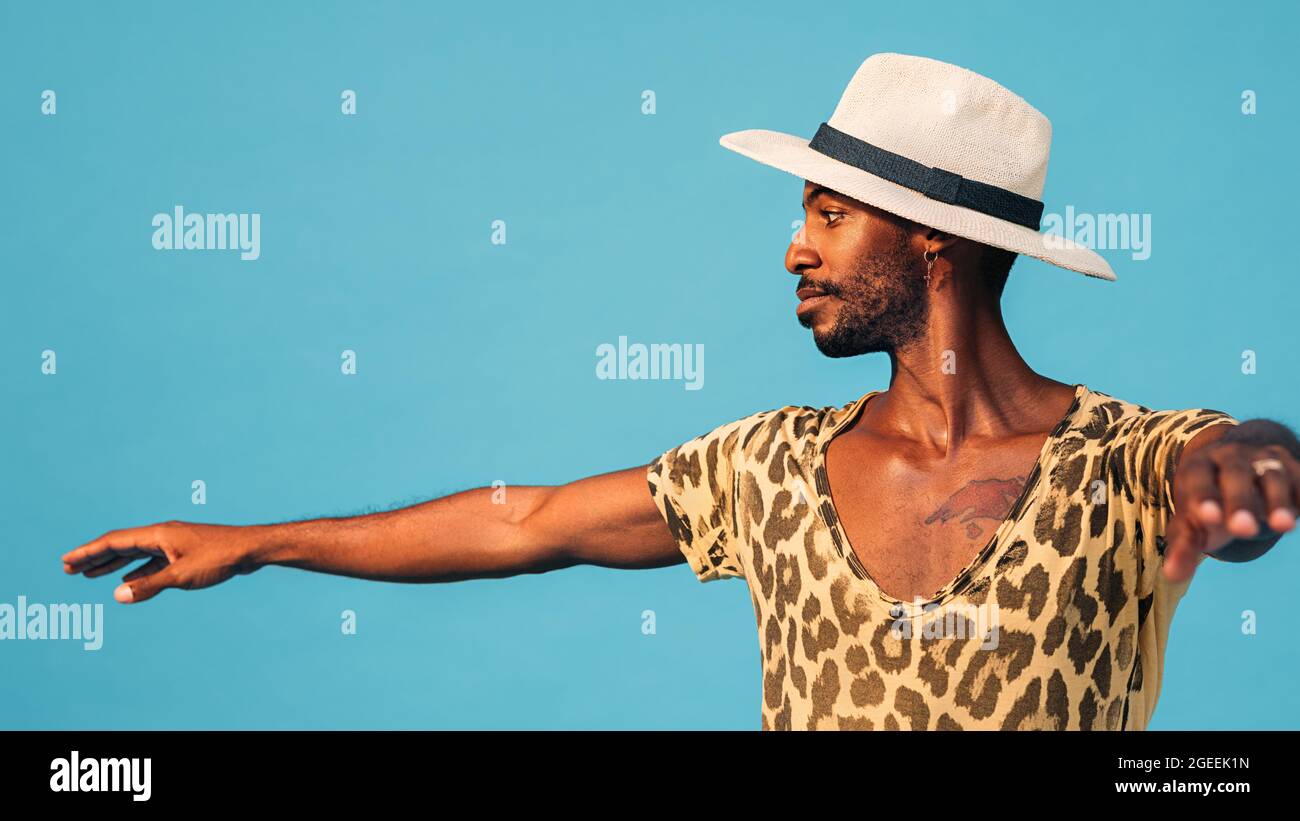 Side view of a young man wearing a straw hat dancing in studio against ...