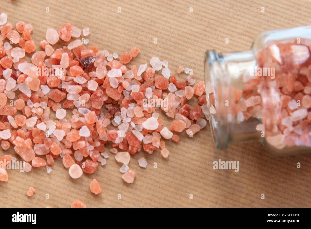Himalayan pink salt scattered from glass bottle, top view. Close up ...