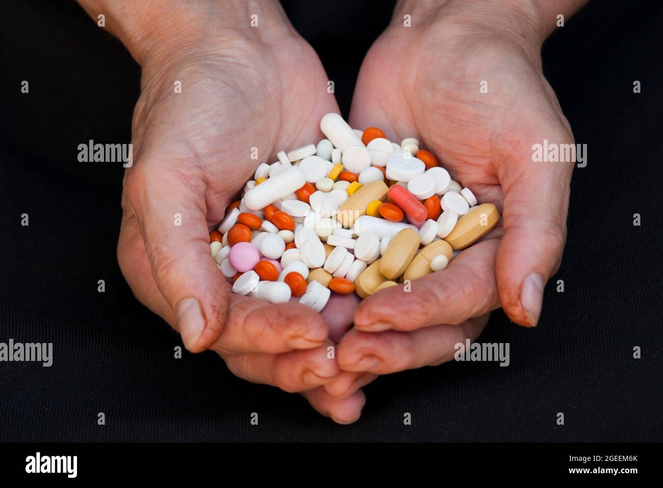 A handful of various pills in female hands over black background Stock ...