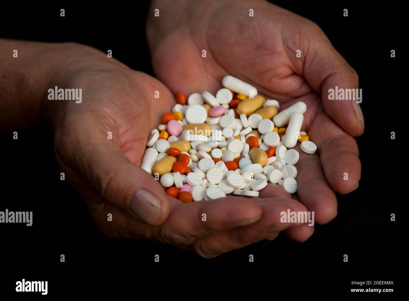 A handful of various pills in male hands over black background Stock ...