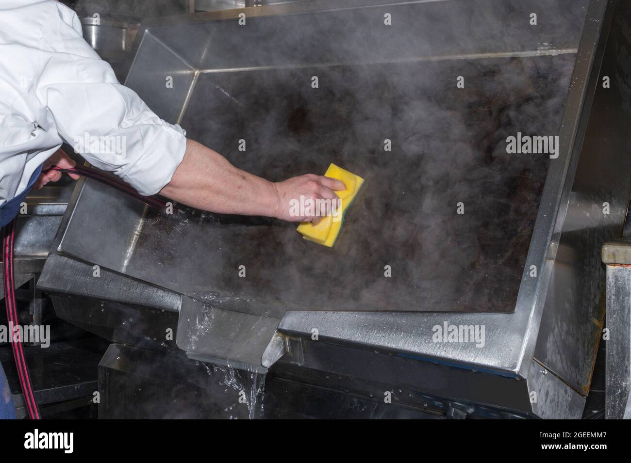 A tilting frying pan is cleaned with a sponge Stock Photo - Alamy