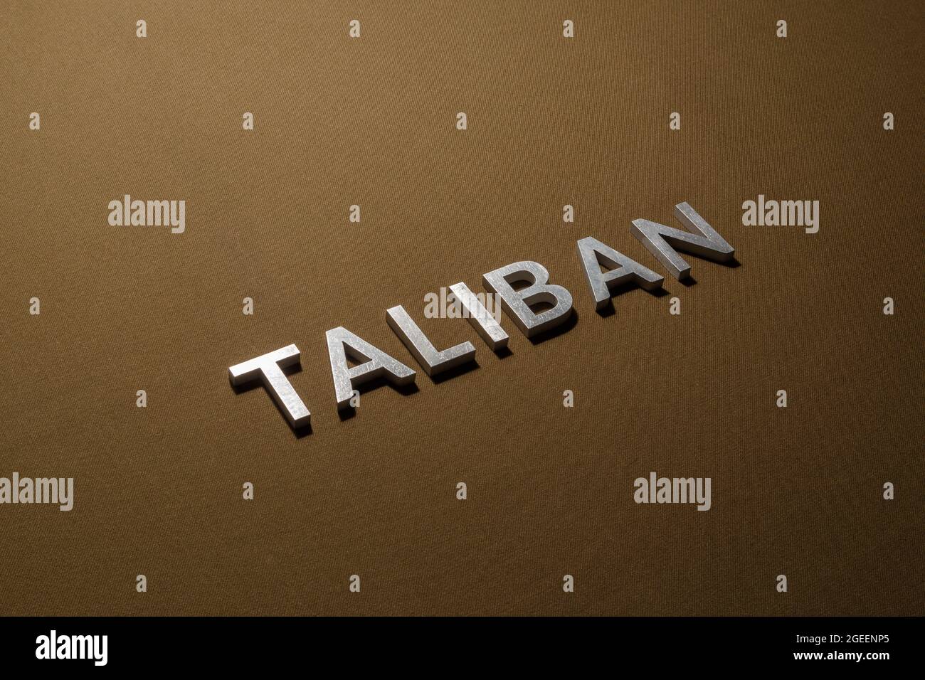 the word taliban laid with silver metal letters on rough tan khaki ...