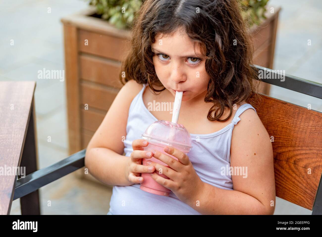 Little girl drinking a strawberry milkshake with angry expression Stock ...