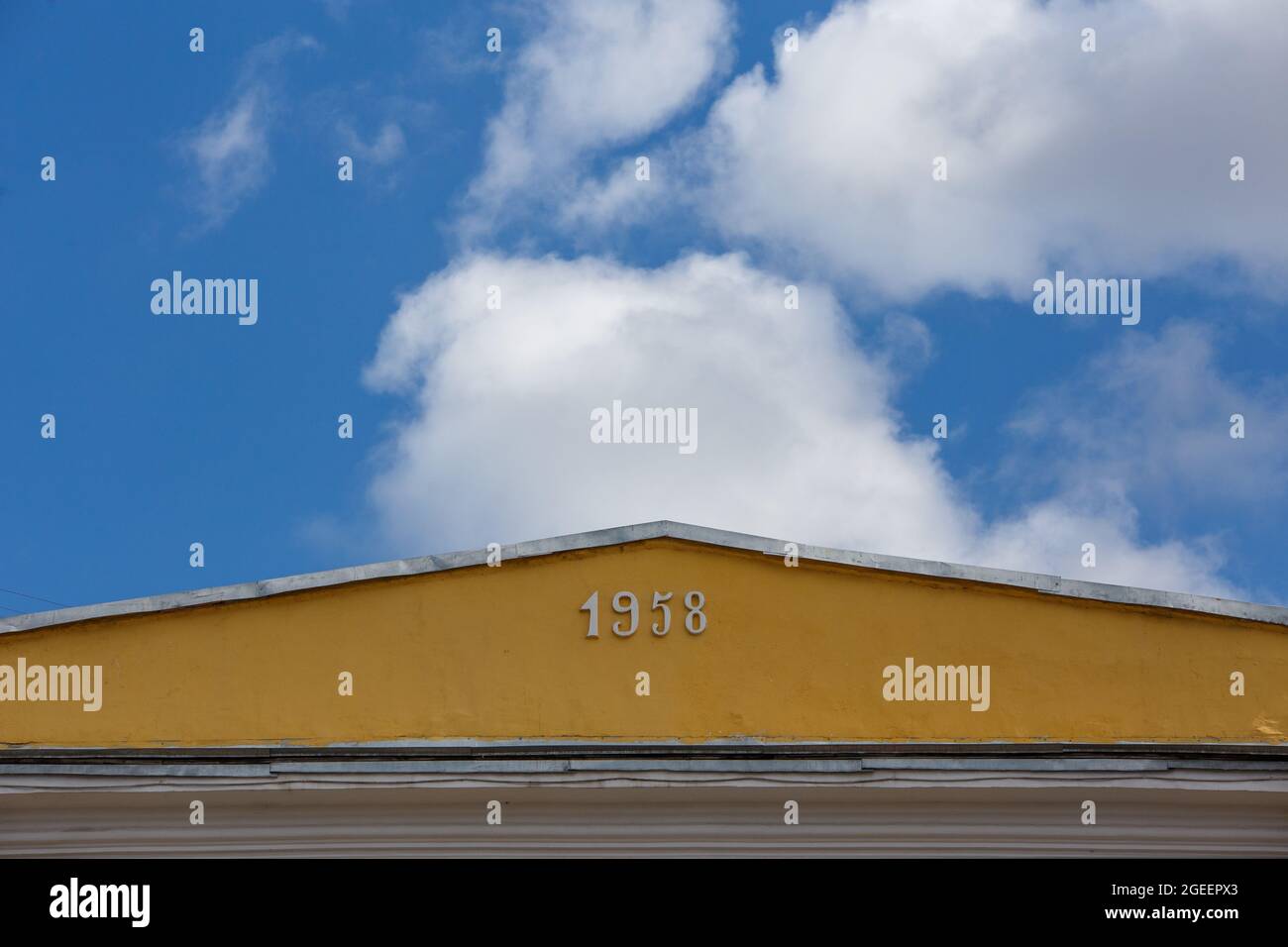 close-up view of yellow roof ridge wit digits 1958 on blue sky with ...