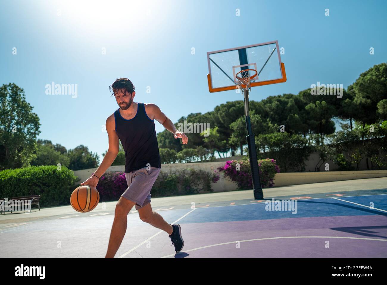 A male basketball player trains himself on a basketball court with a ...