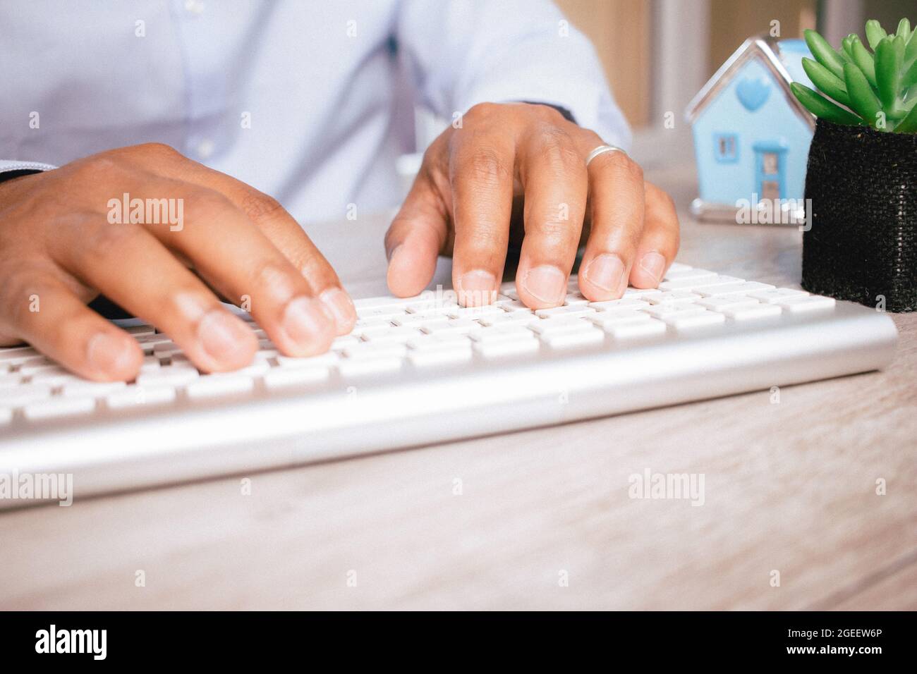 Closeup of a Hispanic man's hands as he types on a keyboard at his desk ...