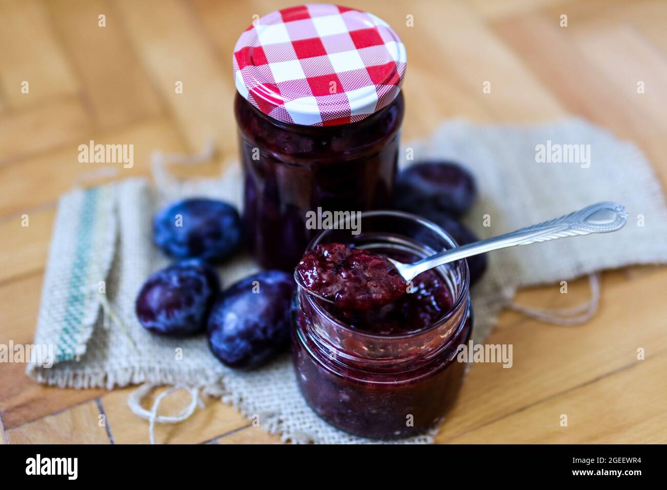 Spoon with plum jam on the retro decorated desk with fruit and glass ...