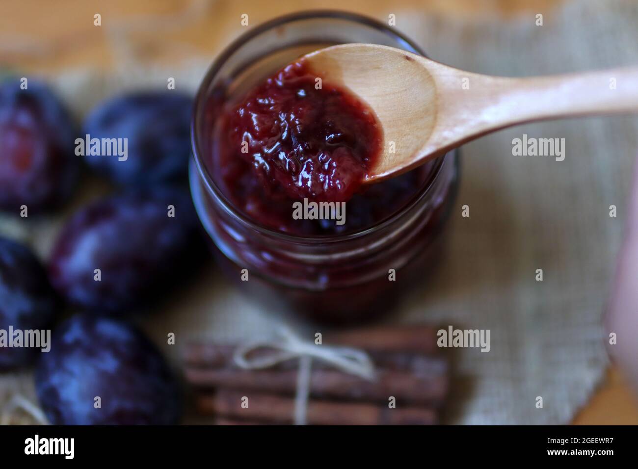 Wooden spoon with plum jam in a glass jar. Healthy food background ...