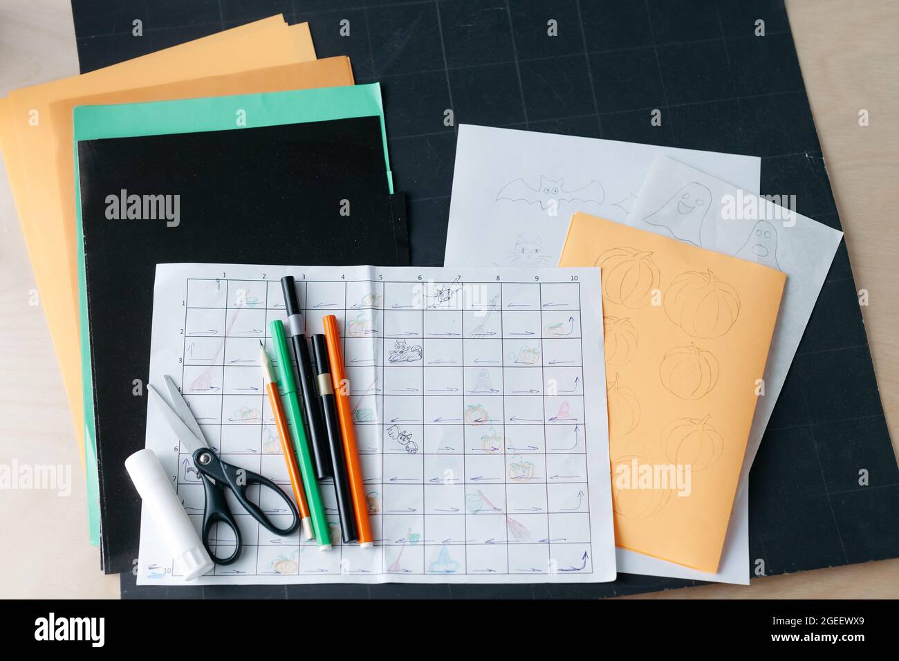 Creating Halloween-themed board game. Sheets of colored paper, sketches ...