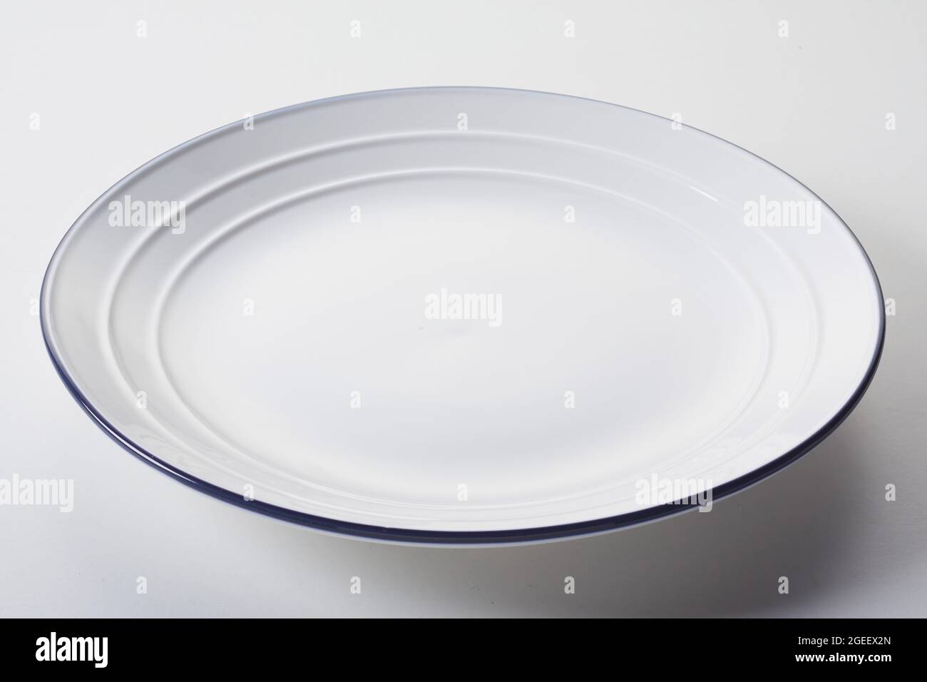 White ceramic plate with a ribbed blue brim on white background Stock ...