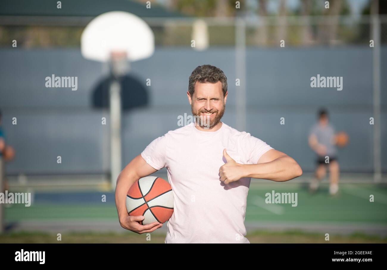 cheerful muscular man athlete basketball player hold ball outdoor ...