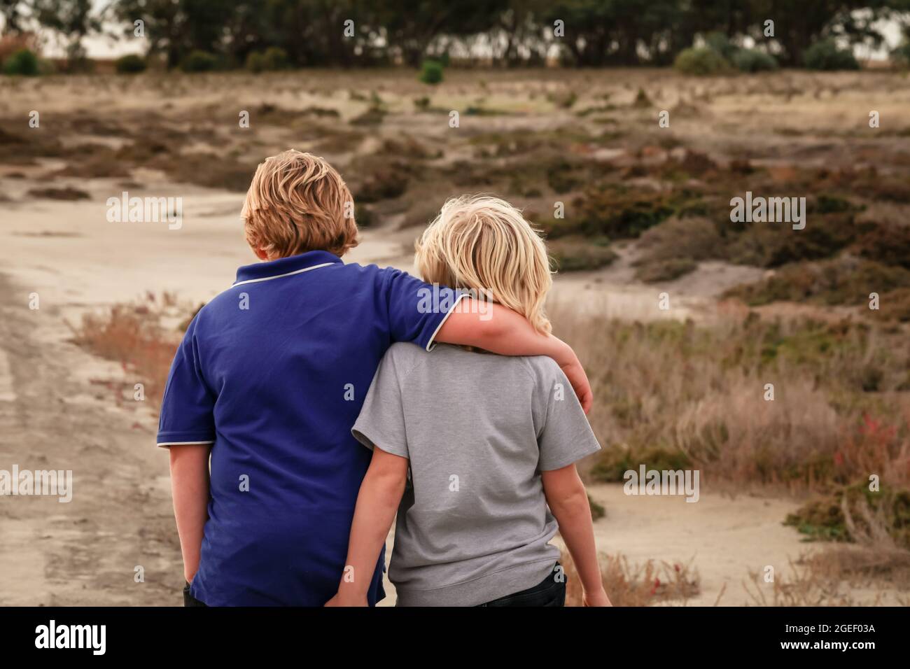 Back view of two brothers exploring a desolate dry lake in Australia ...