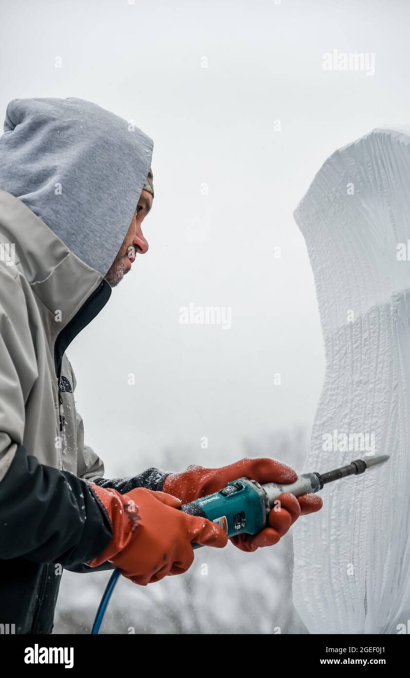 Professional ice carver sculpting block of ice Stock Photo - Alamy