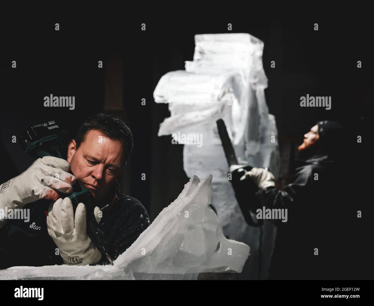 Professional ice carver sculpting block of ice Stock Photo - Alamy