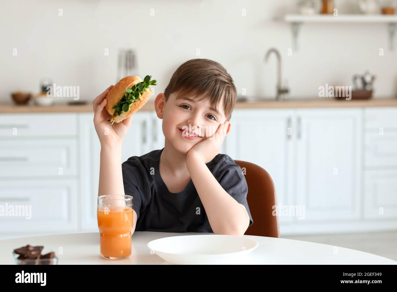 Little boy with tasty vegan burger in kitchen Stock Photo - Alamy