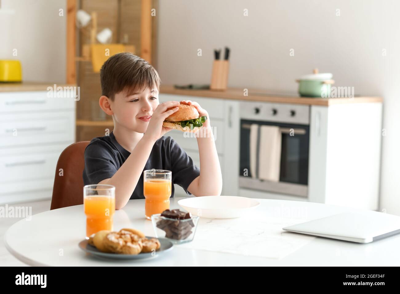 Little boy with tasty vegan burger in kitchen Stock Photo - Alamy
