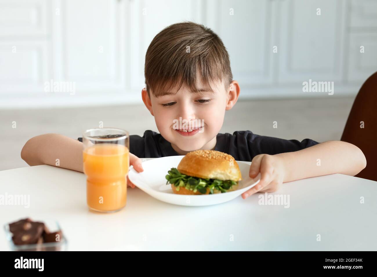 Little boy with tasty vegan burger in kitchen Stock Photo - Alamy