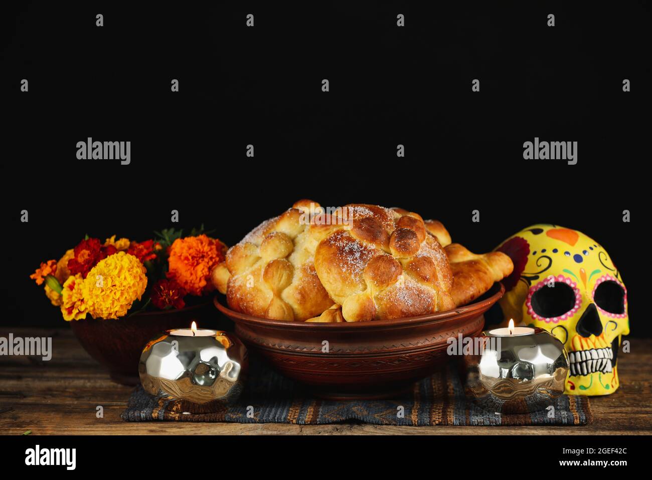 Bread of the dead and painted skull on table against dark background ...
