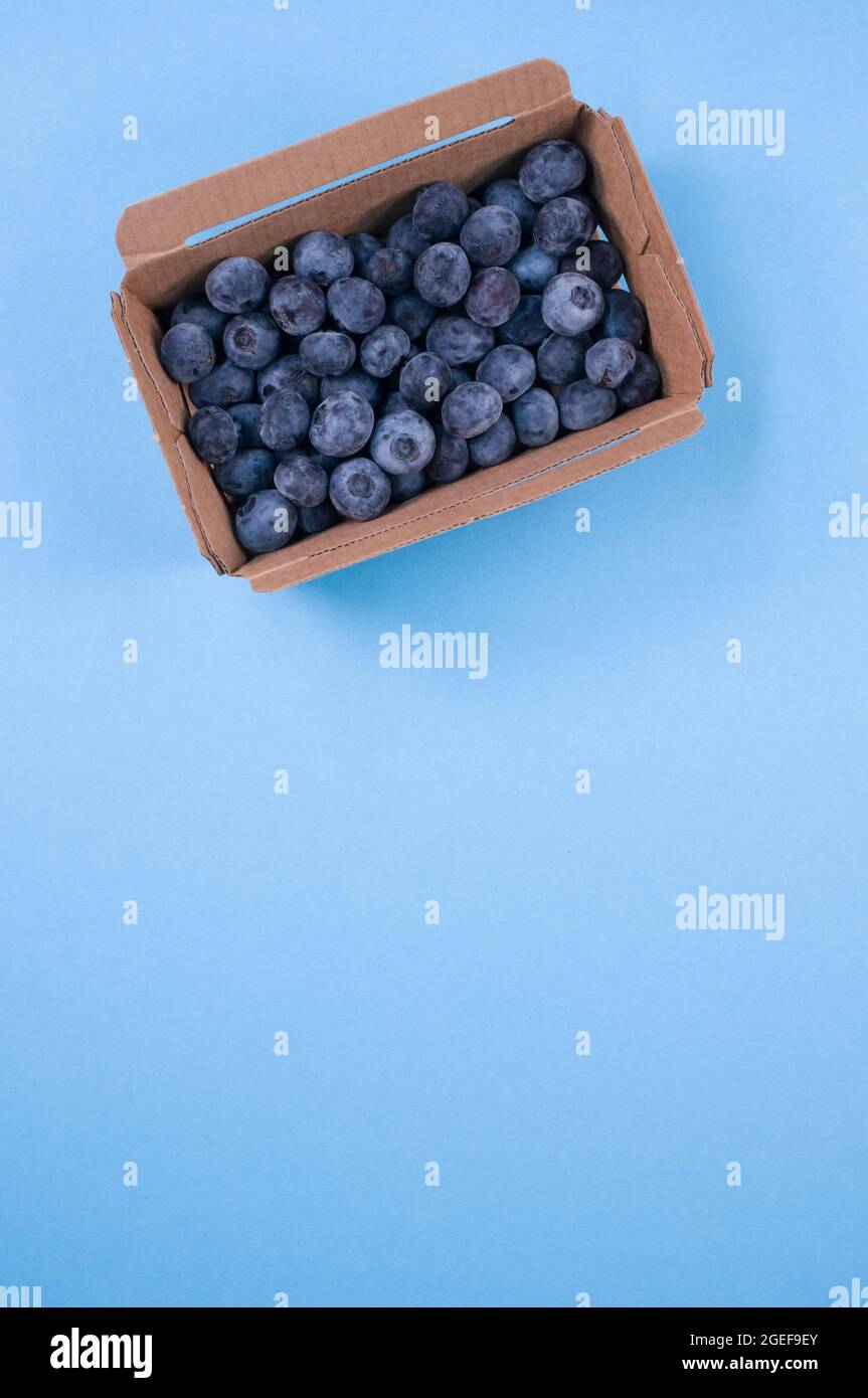 Top view of delicious blueberries in a paper box isolated on a blue ...