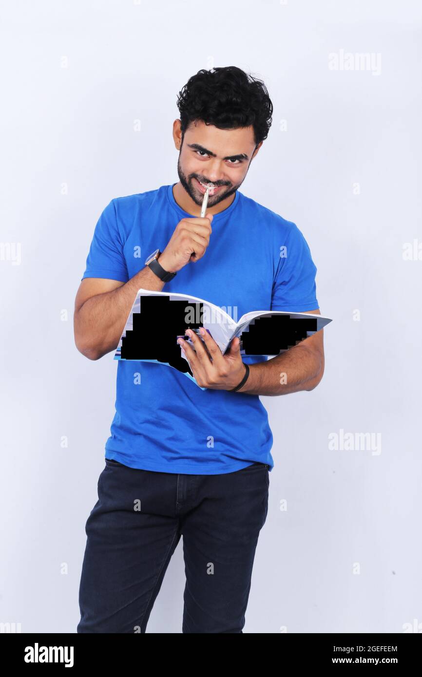 Indian young man reading book while holding pen on white background ...