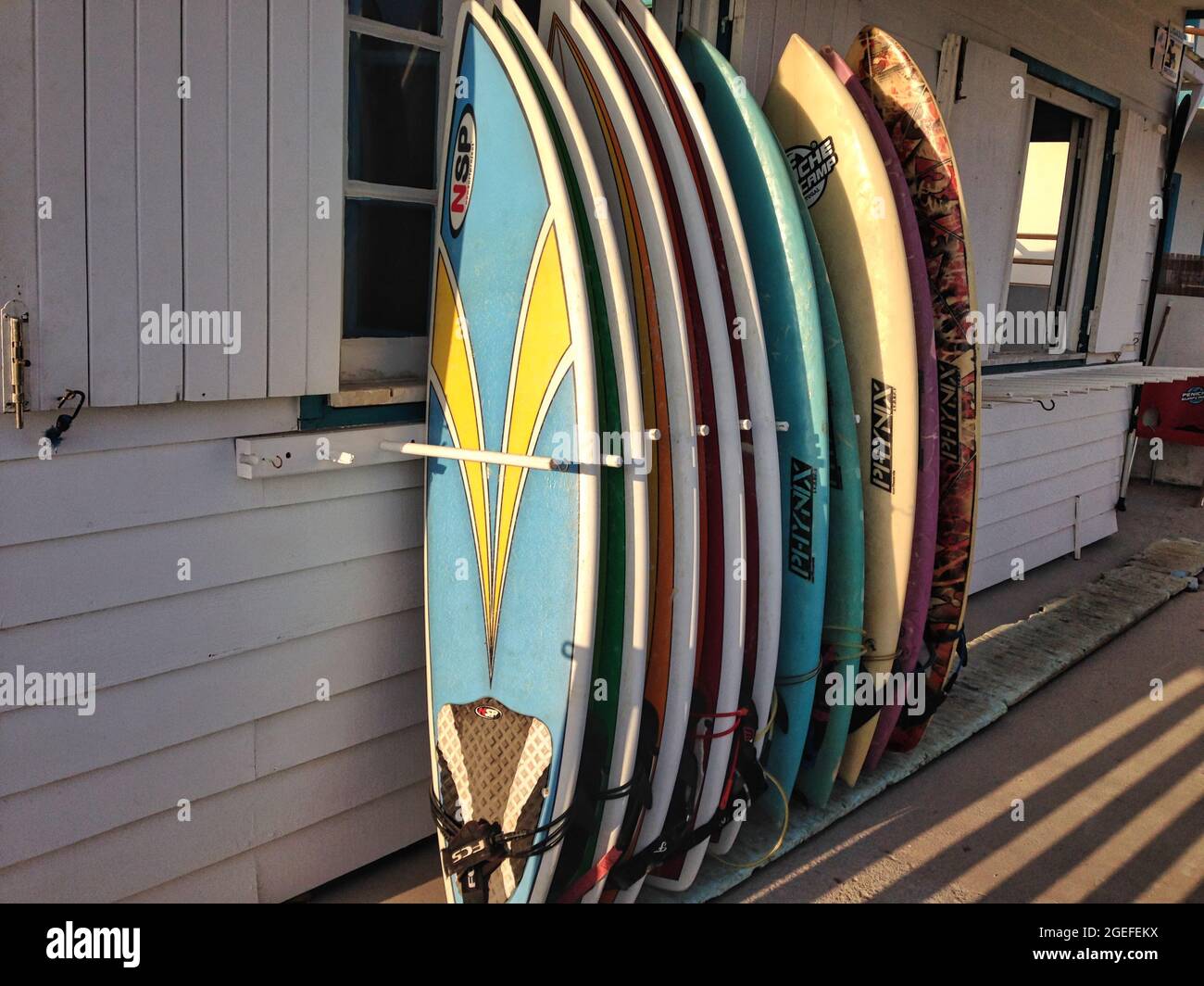Lineup of colorful surfing boards near a wooden building in the ...