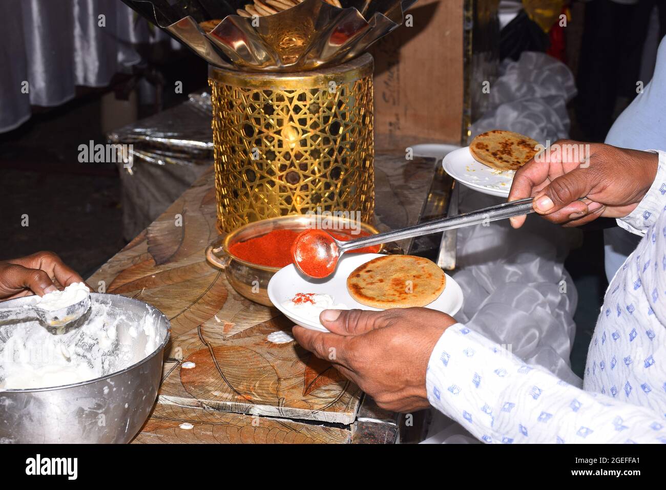Hand of Indian man carrying Curd Pea Paratha in his plate by a spoon ...