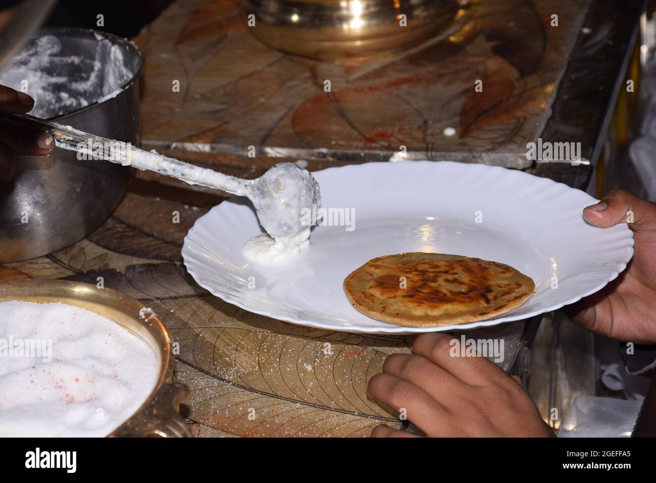 Hand of Indian man carrying Curd Pea Paratha in his plate by a spoon ...